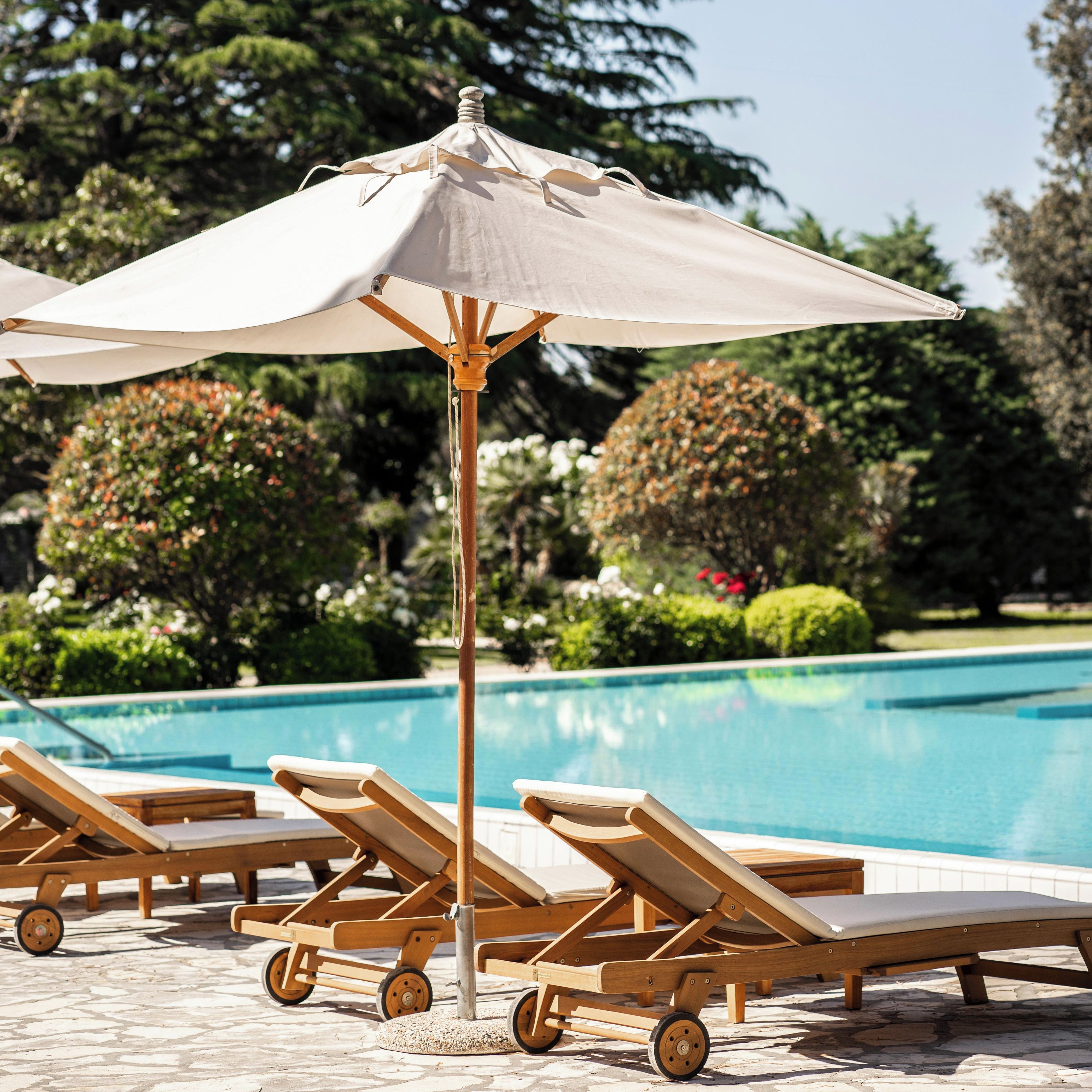 Área de piscina com espreguiçadeiras e guarda-sol.