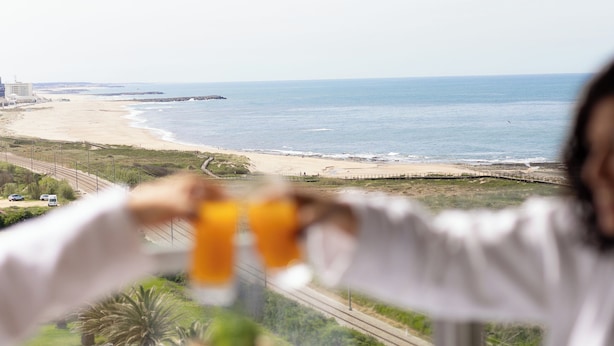 Uma mesa de jantar com itens de café da manhã e vista para a praia e o oceano.
