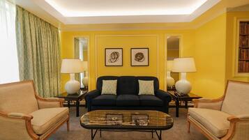Uma sala de estar com um sofá, duas poltronas, uma mesa de centro e duas luminárias.