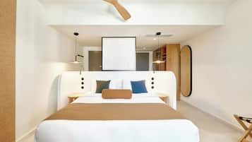 Quarto moderno com uma cama grande, ventilador de teto e vista para o banheiro.