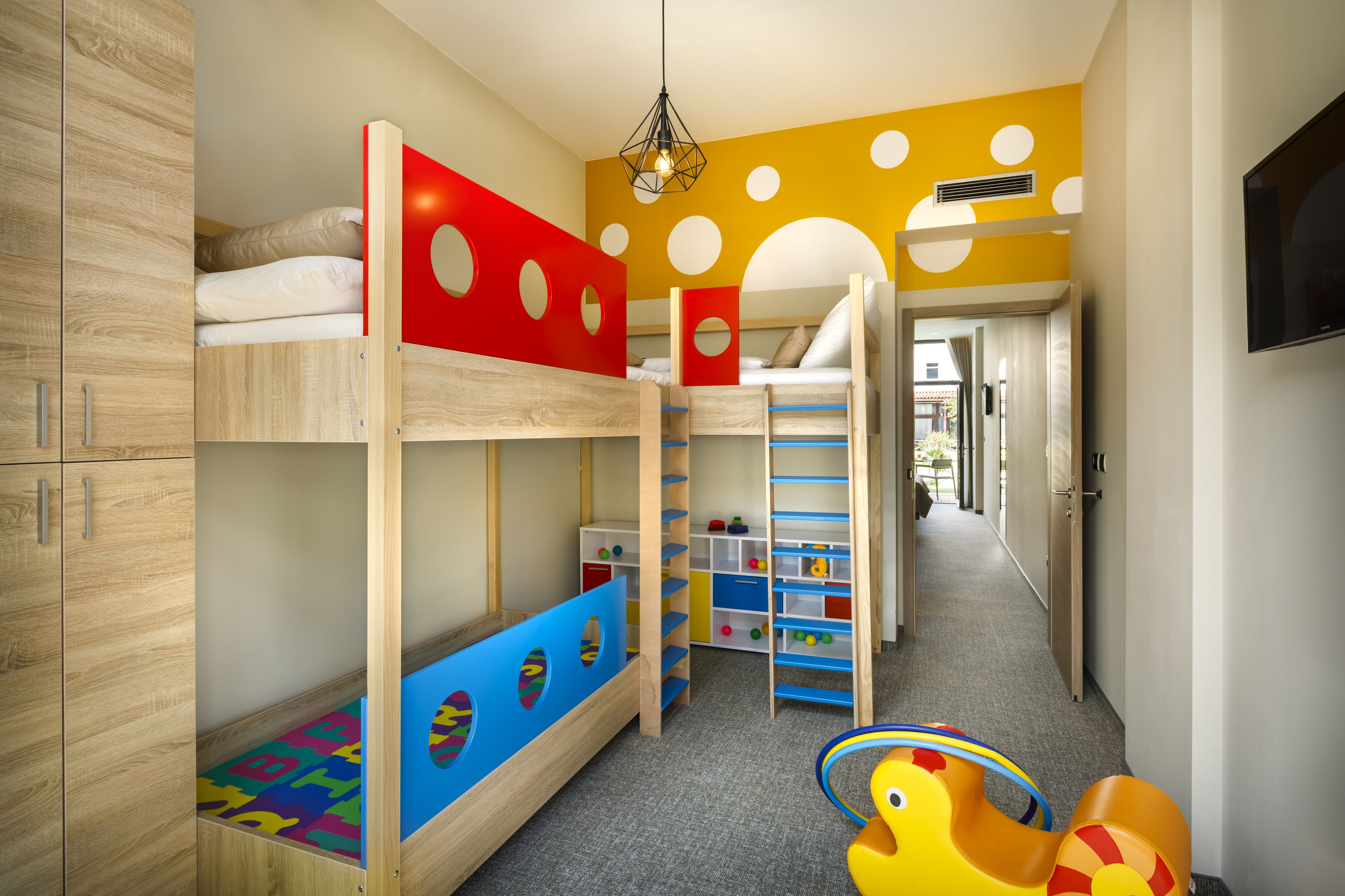 Quarto infantil com beliches, espaço de brincadeiras e corredor que dá acesso a outros cômodos.