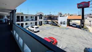 Um estacionamento com vários andares, céu claro, um carro esportivo vermelho e uma placa com 'LEXMAR'.