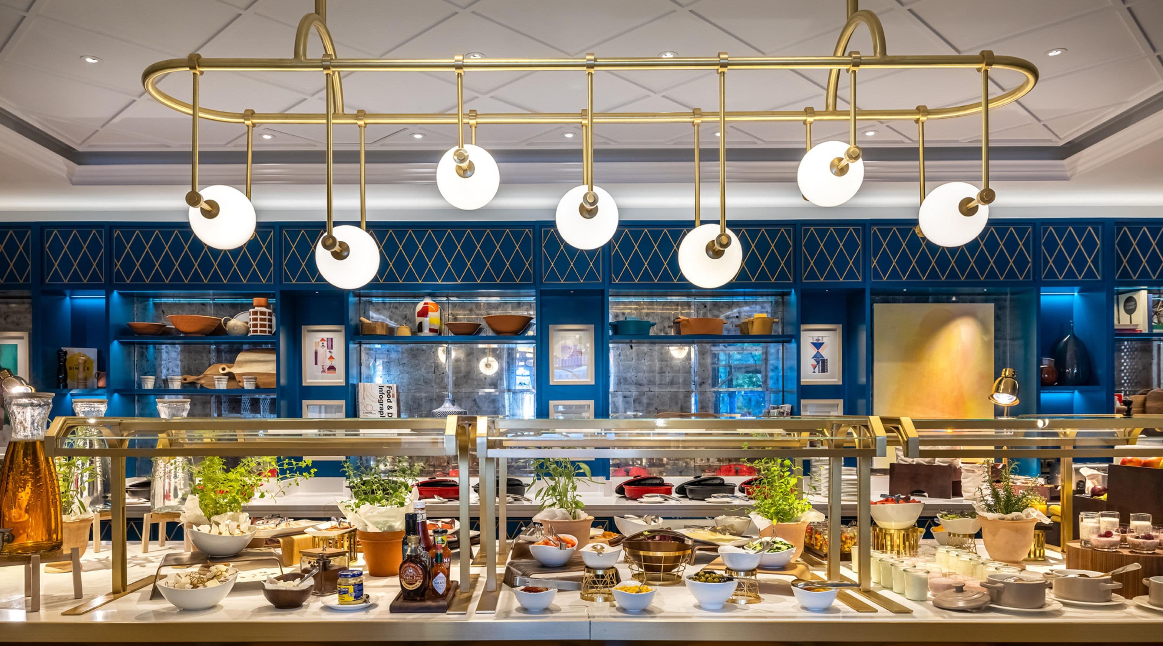 Uma área de buffet com diversos tipos de comida e um lustre decorativo.