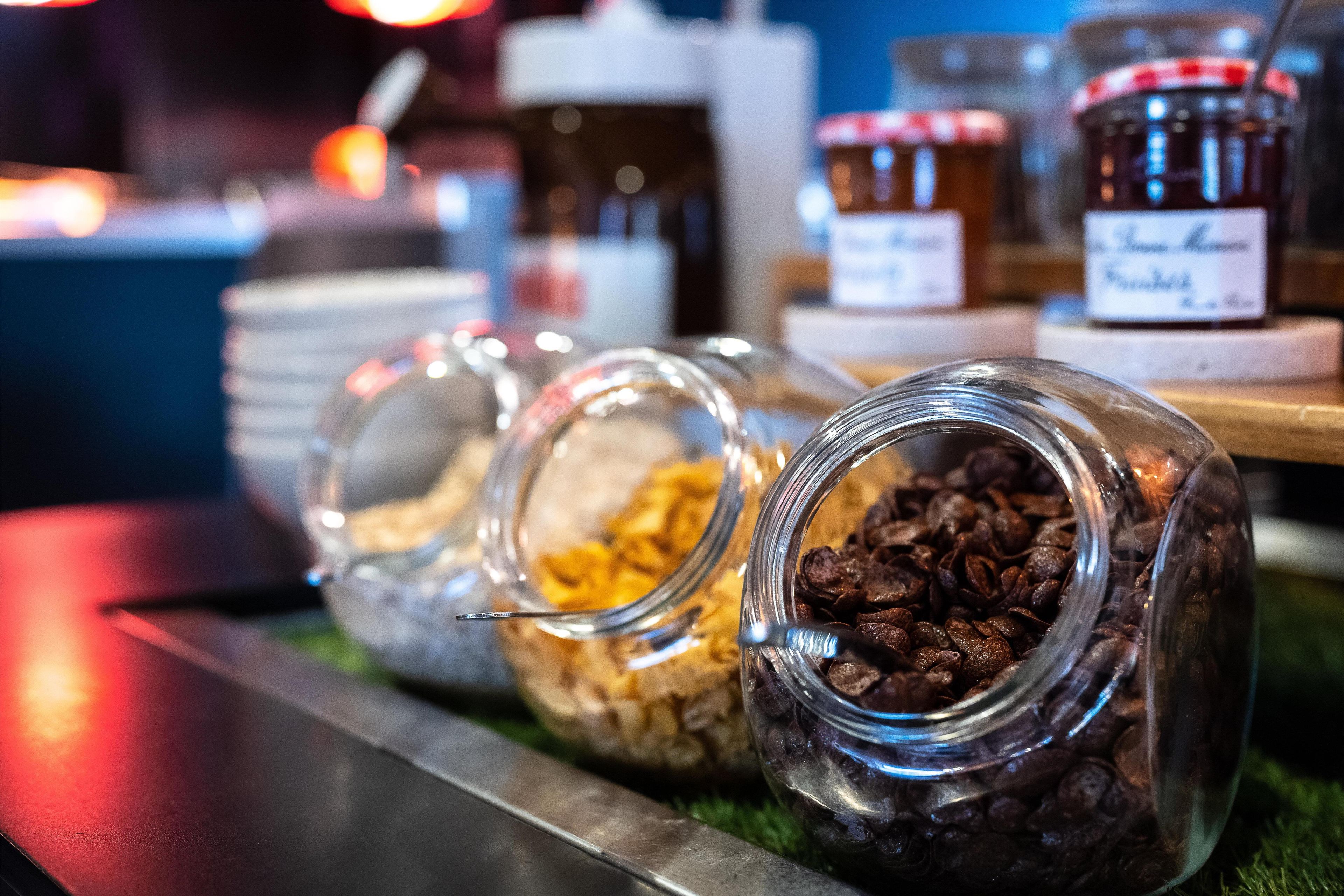 Buffet com diversos alimentos em recipientes de vidro.
