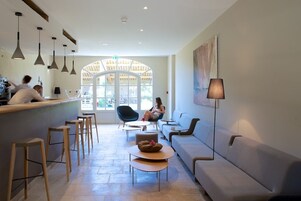 Um interior moderno com uma área de recepção, assentos e uma janela grande.
