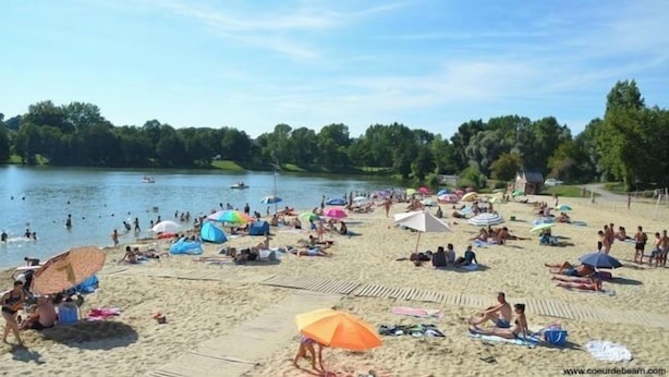 Uma praia com pessoas se banhando e tomando sol.