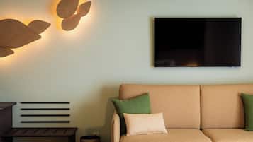 Uma sala de estar moderna com um sofá, uma TV de tela plana e um luminário fixado na parede.