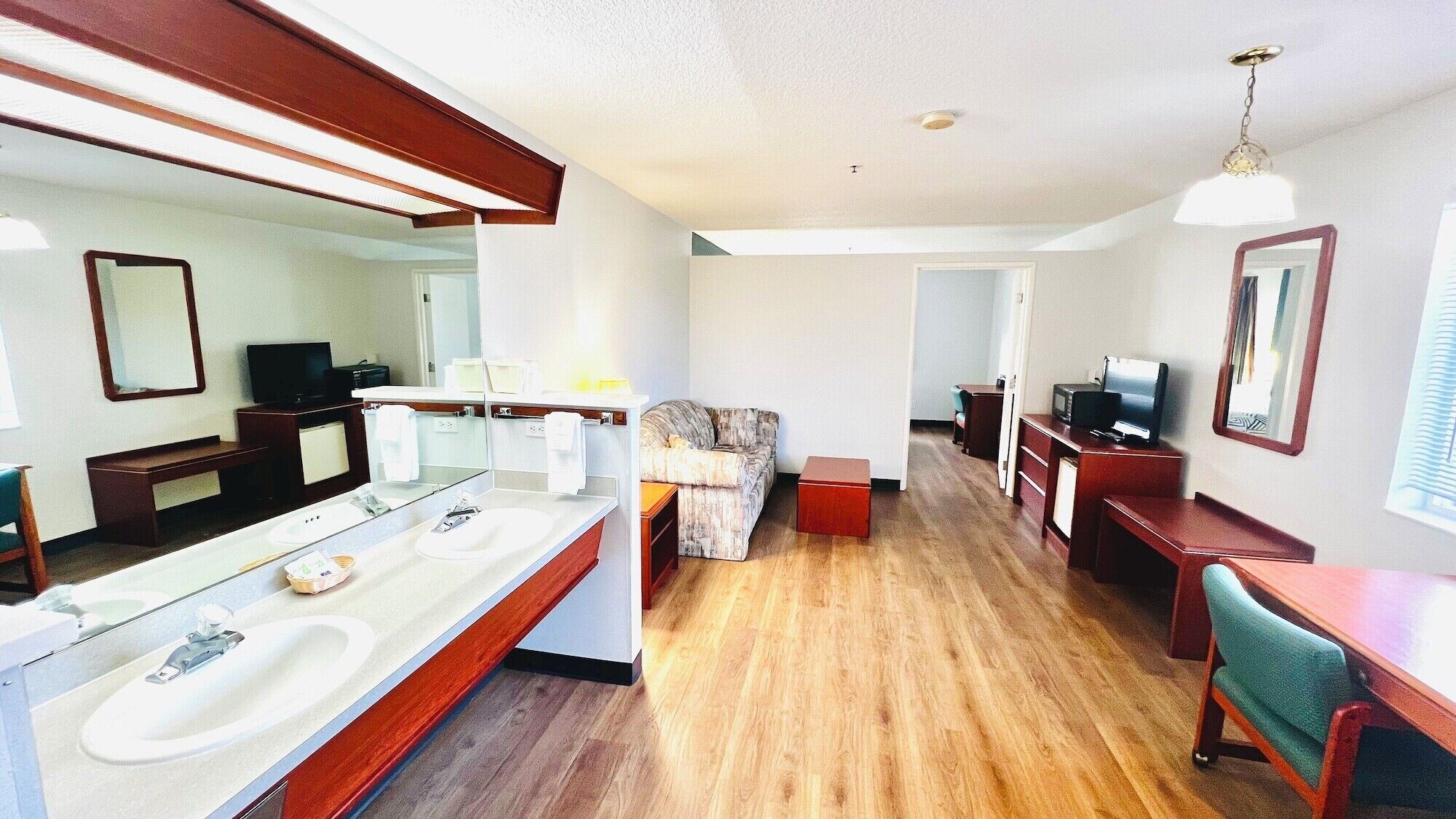 Quarto de hotel moderno com um banheiro amplo, um sofá, uma TV e um espaço de refeições.