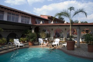 Uma área de piscina com espreguiçadeiras e plantas em vasos.