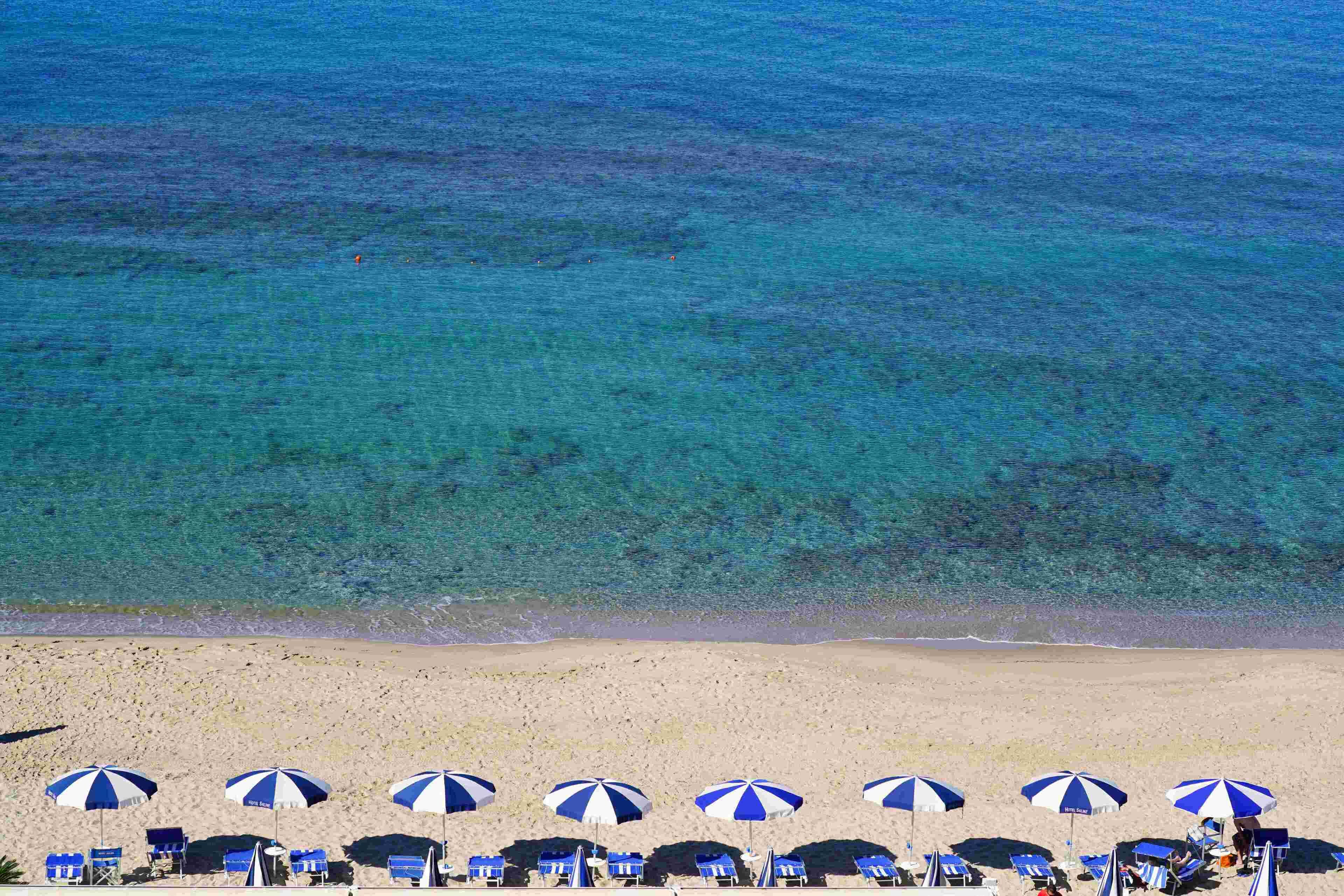Praia particular, areia branca, espreguiçadeiras, guarda-sóis 