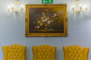 Quarto com pintura floral, duas poltronas estofadas em amarelo e um candelabro.