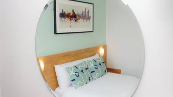 Um quarto circular com uma cama, cabeceira e um quadro na parede.
