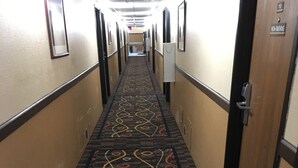 Corredor de hotel com carpete estampado, portas e placa indicando área para não fumantes.