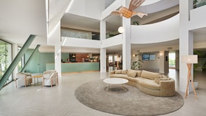 Um hall amplo com área de estar central, escada e balcão de recepção.