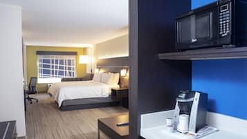 Quarto de hotel com cama, mesa de cabeceira e máquina de café.