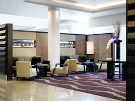 Um lobby moderno com área de estar, uma coluna grande e um vaso decorativo com flores.