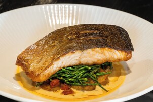 Um prato com um pedaço de peixe, vagem e um molho cremoso.