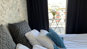 Quarto de hotel com uma cama, cortinas escuras e vista para a varanda externa.