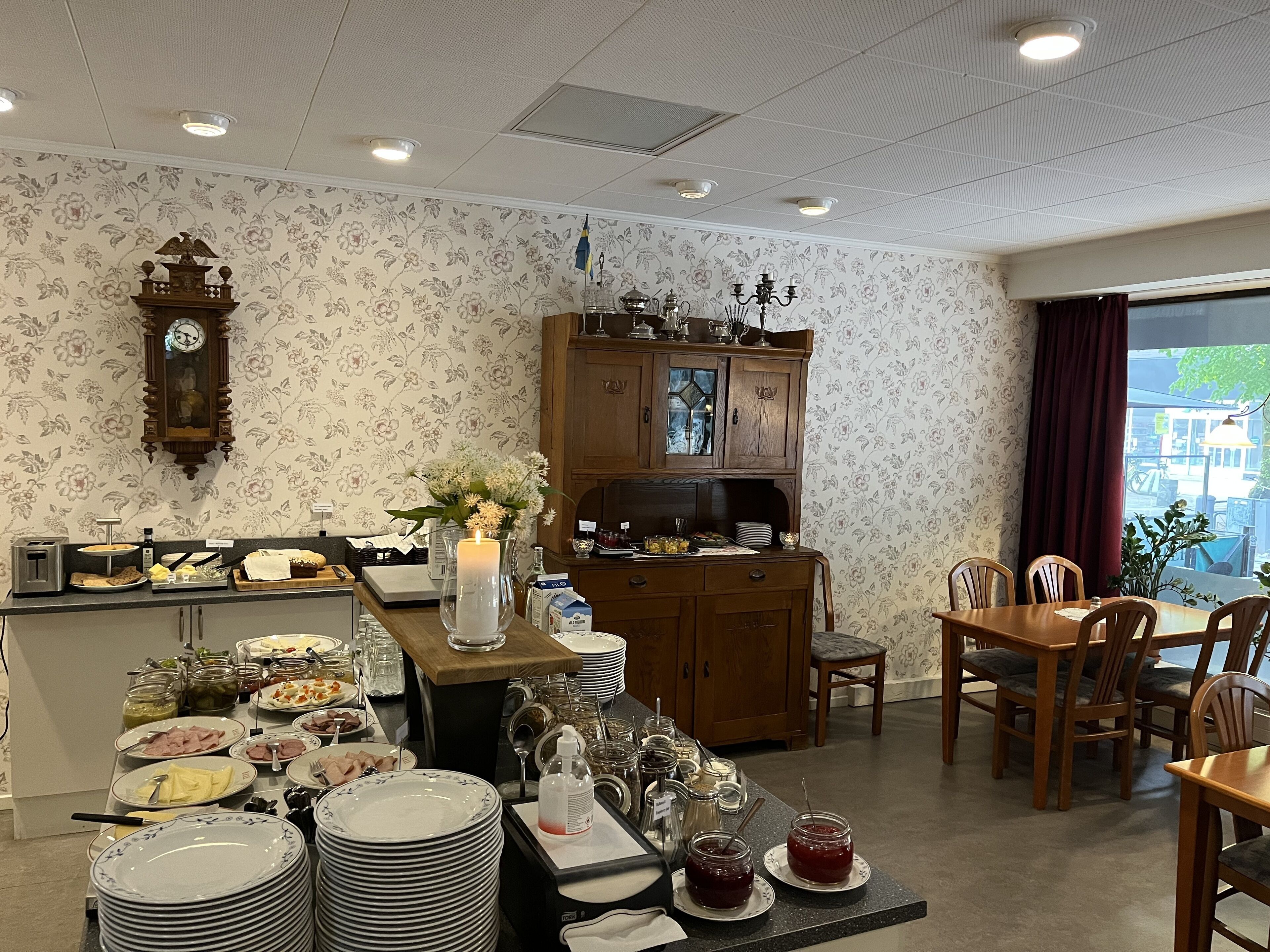 Uma área de refeições com serviço de buffet, um armário de madeira e um relógio na parede.