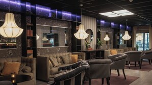 Um lobby de hotel moderno com um sofá, cadeiras listradas e uma área de bar.