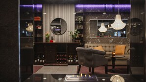 Uma área de bar moderna com um sofá, cadeiras listradas e um espaço para vinhos.
