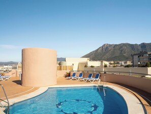 Piscina no terraço com espreguiçadeiras e vista para a montanha.