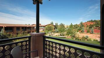 Uma varanda com vista para um jardim ajardinado e edifícios ao fundo.