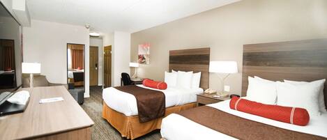 Quarto de hotel com duas camas, uma escrivaninha, uma cadeira e uma televisão.