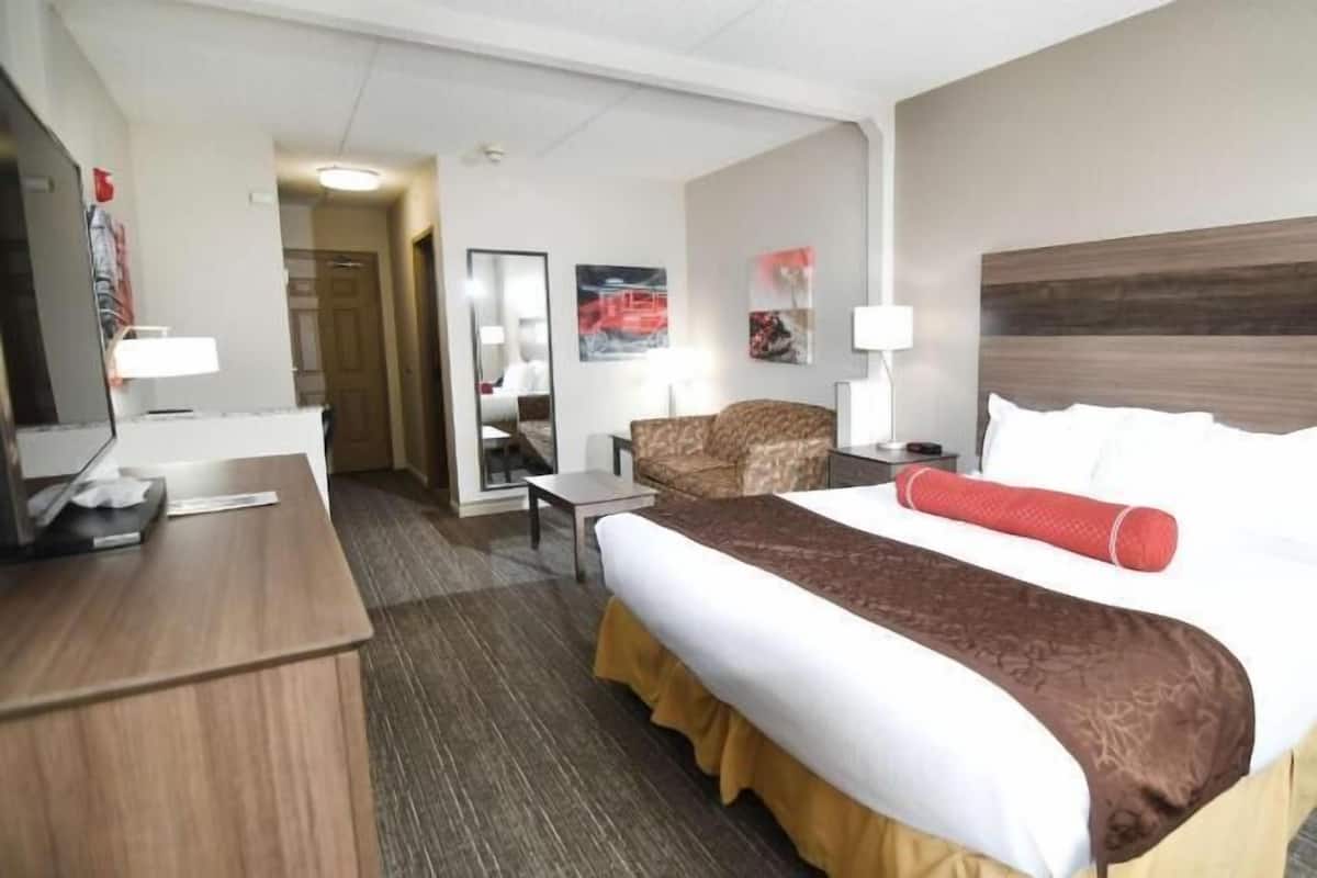 Quarto de hotel com uma cama grande, uma escrivaninha, uma cadeira, uma mesa de cabeceira e um espelho.