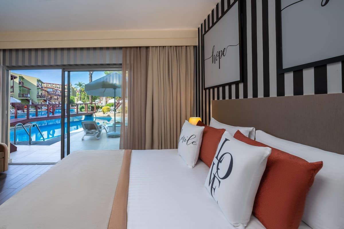 Quarto de hotel com uma cama grande, vista para uma piscina e um aviso na parede com a palavra 'esperança'.