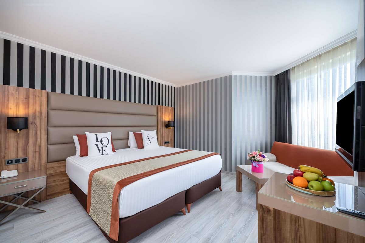Quarto de hotel moderno com uma cama grande, uma escrivaninha e uma televisão.