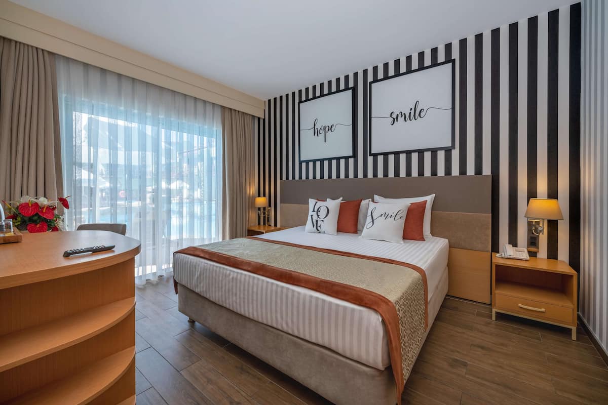 Quarto de hotel com uma cama grande, uma mesa e vista para a cidade.