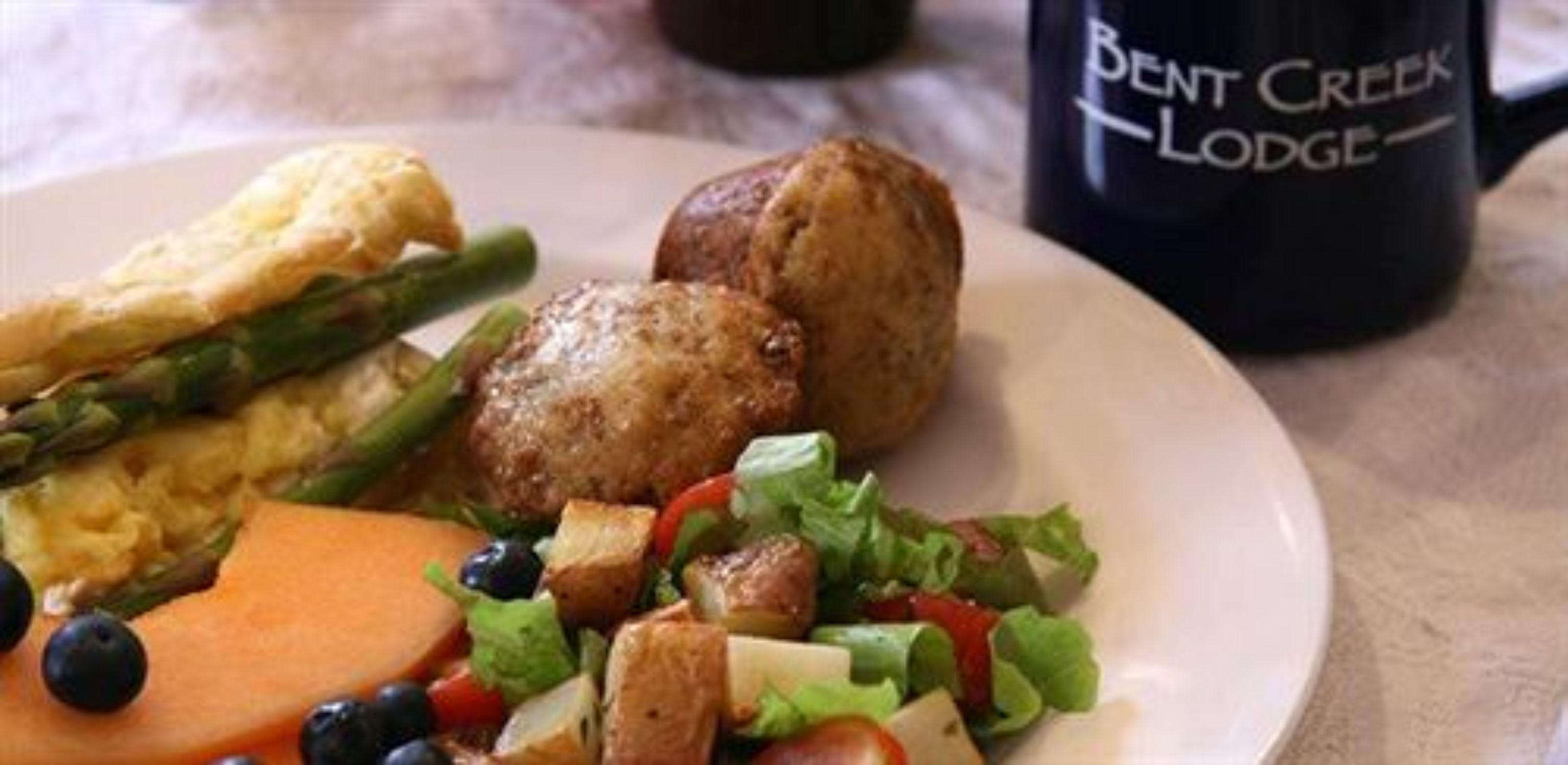 Prato de comida com aspargos, bolacha e salada de tomate e azeitonas.