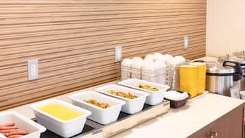 Disposição de buffet com diversos recipientes de comida e um espaço para café.