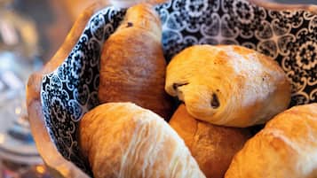 Uma tigela de madeira cheia de croissants e outros doces.
