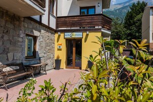 Um hotel com fachada de pedra, varanda de madeira e uma placa com a inscrição "HOTEL AU SOLEIL".