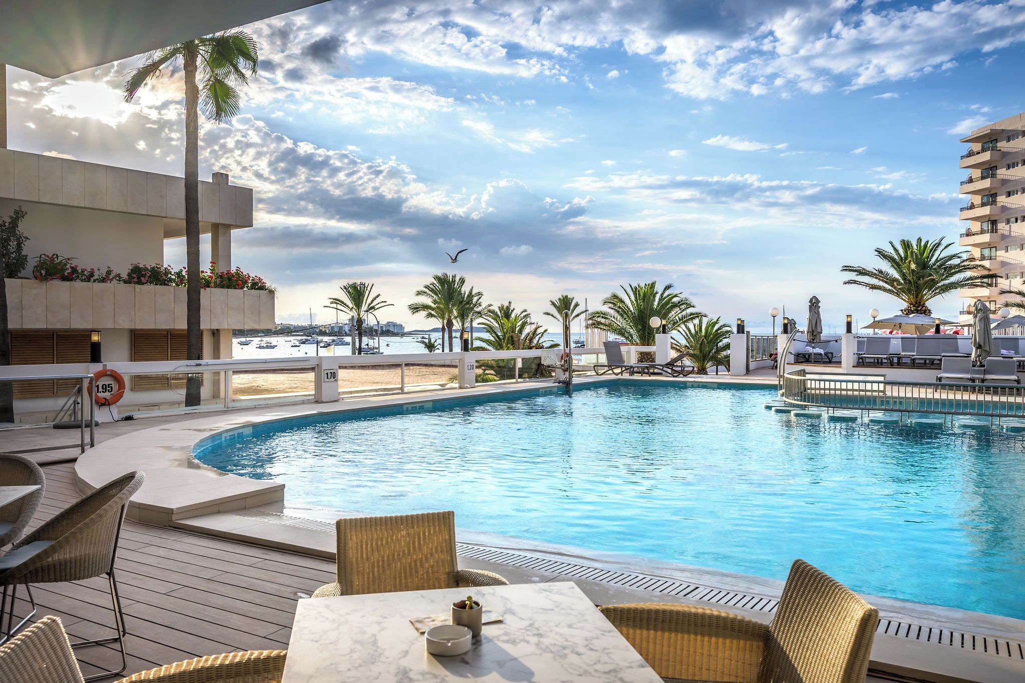 Área de piscina com espreguiçadeiras e vista para o mar.