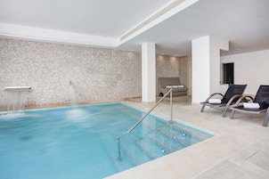 Piscina com piso de azulejos, um recurso aquático e duas espreguiçadeiras.