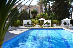 Piscina com toldos brancos, espreguiçadeiras e água azul cristalina.