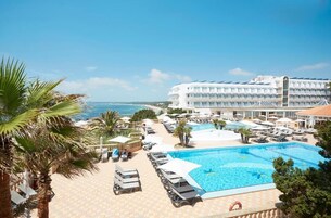 Um resort com uma piscina grande, espreguiçadeiras e vista para o oceano.