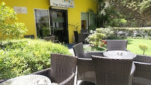 Área externa com mesas e cadeiras de vime e um letreiro para o Citrus Café.