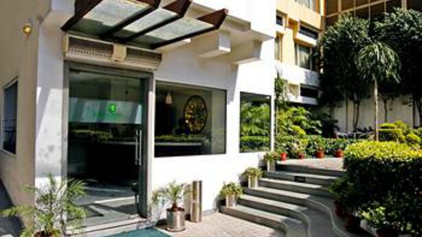 Um edifício moderno com entrada de vidro, degraus externos e vasos de plantas.