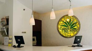 Um balcão de recepção com dois monitores de computador, um adorno circular na parede e luminárias pendentes.