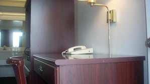 Bancada de recepção de hotel com telefone, abajur e espelho.