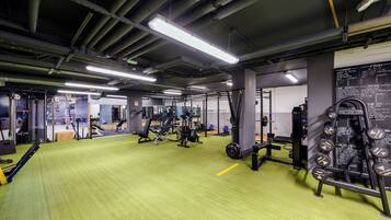 Uma academia com diversos equipamentos de exercício, incluindo aparelhos de musculação, pesos livres e um banco.
