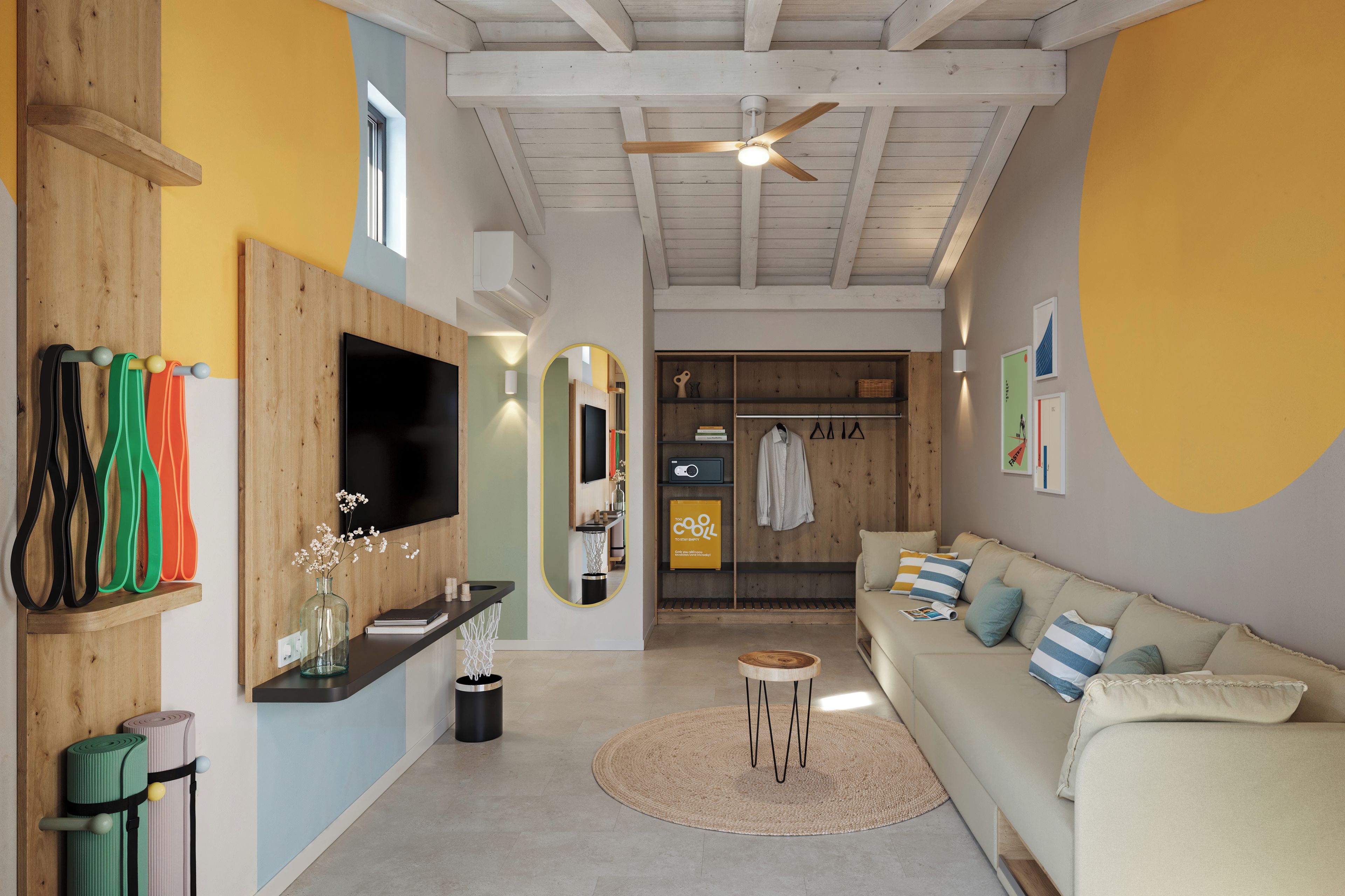 Uma sala de estar moderna com televisão de tela plana, vigas de madeira, ventilador de teto, sofá e tapete redondo.