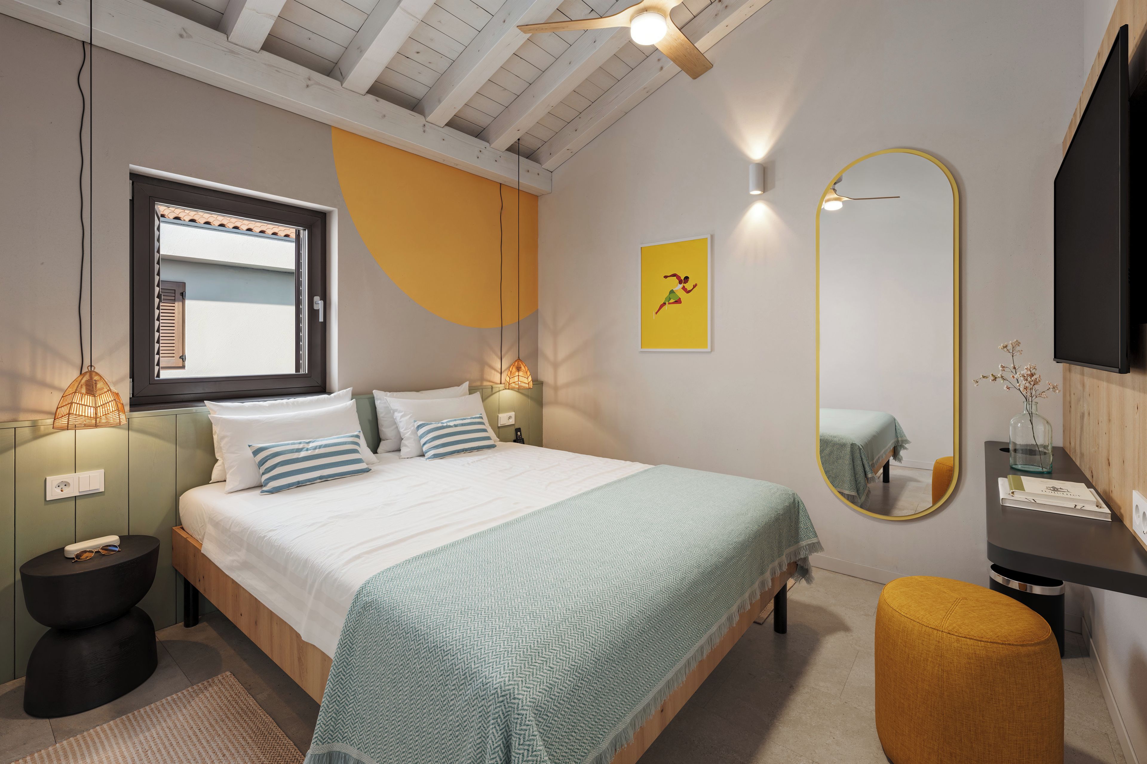 Quarto com cama, mesas de cabeceira, espelho, janela e ventilador de teto.