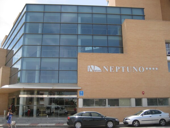 Hotel Neptuno, com fachada moderna em vidro e uma base de tijolos.