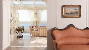 Quarto com vista para o mar, uma escadaria, um sofá e um quadro na parede.