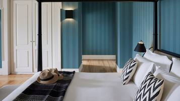 Quarto de hotel com cama, mesa de cabeceira, luminária e janela.